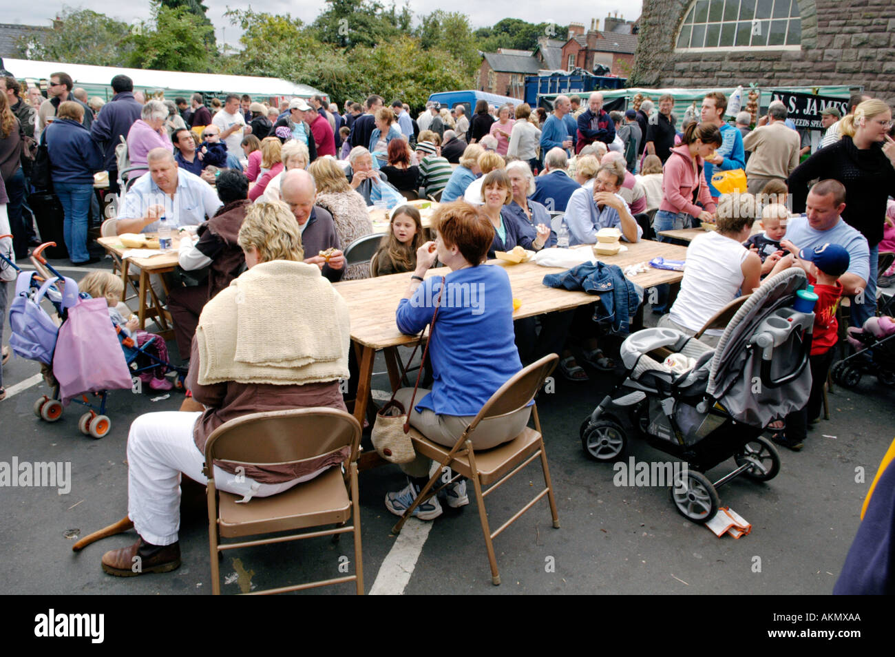 People eating at tables and browsing stalls in a courtyard setting at ...