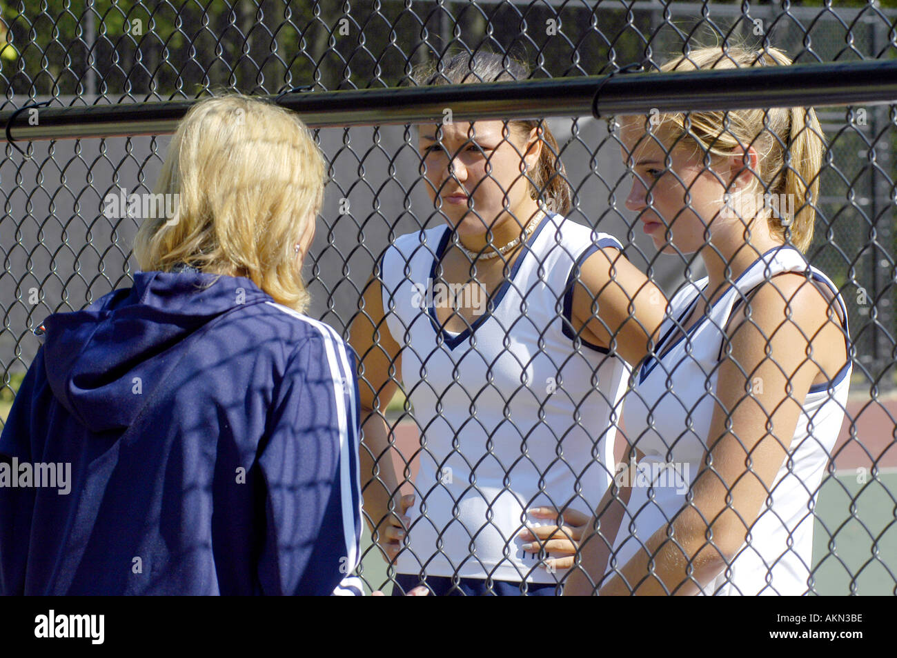 Female doubles match at a high school tennis meet coach talks strategy ...