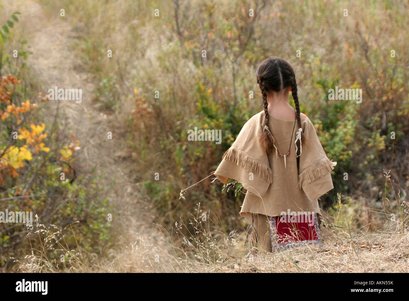 A young Native American Indian boy in braids walking down a path ...