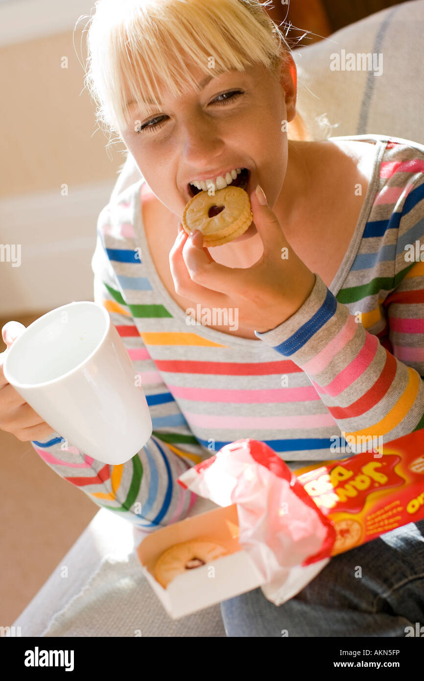 Woman eating biscuits with drink Stock Photo - Alamy
