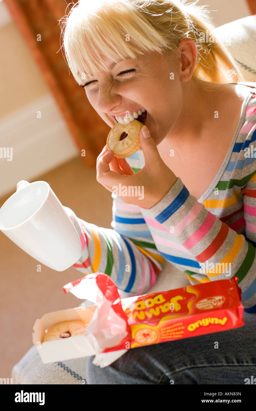 Woman eating biscuits with drink Stock Photo - Alamy