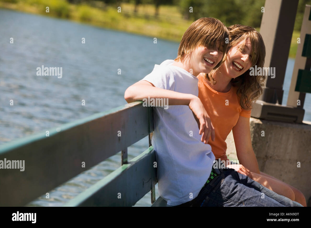 Teenagers sitting on a bench by water Stock Photo - Alamy