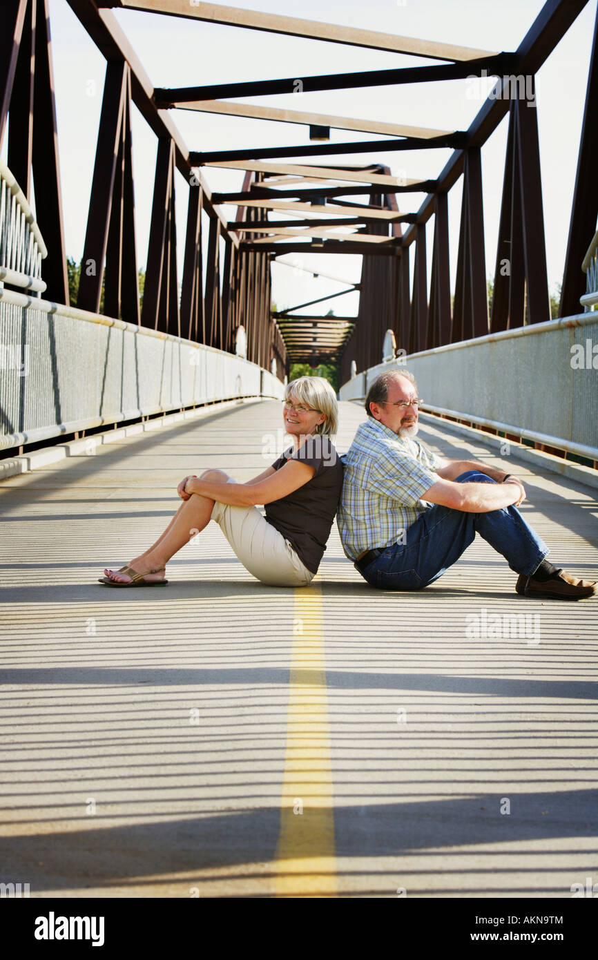 Husband and wife sitting on the middle of a bridge Stock Photo - Alamy