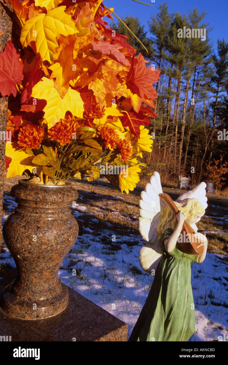 Artificial Flowers with an angel statue next to an headstone in a ...