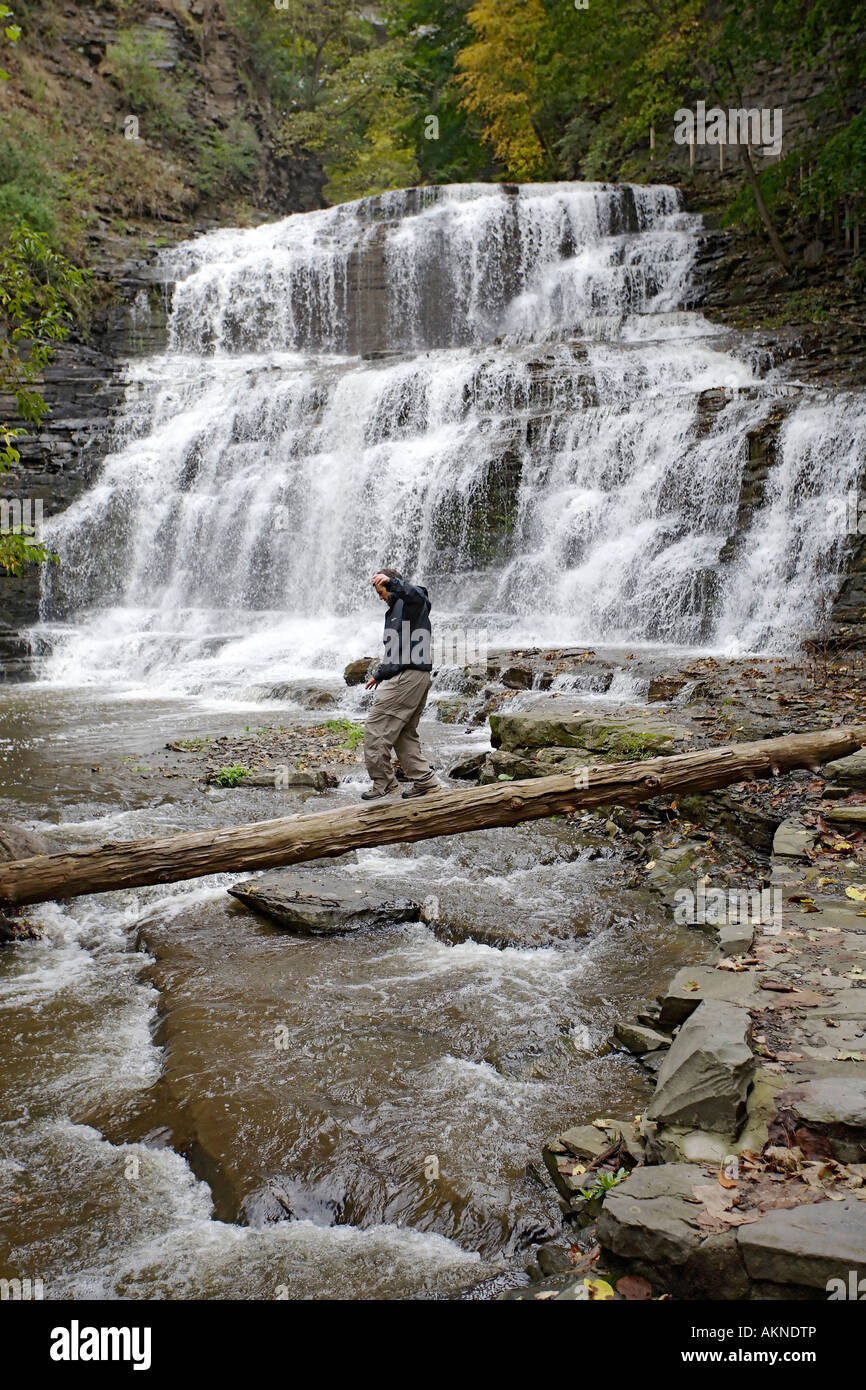 Man walking on log over river by waterfall. Cascadilla Creek, Ithaca ...