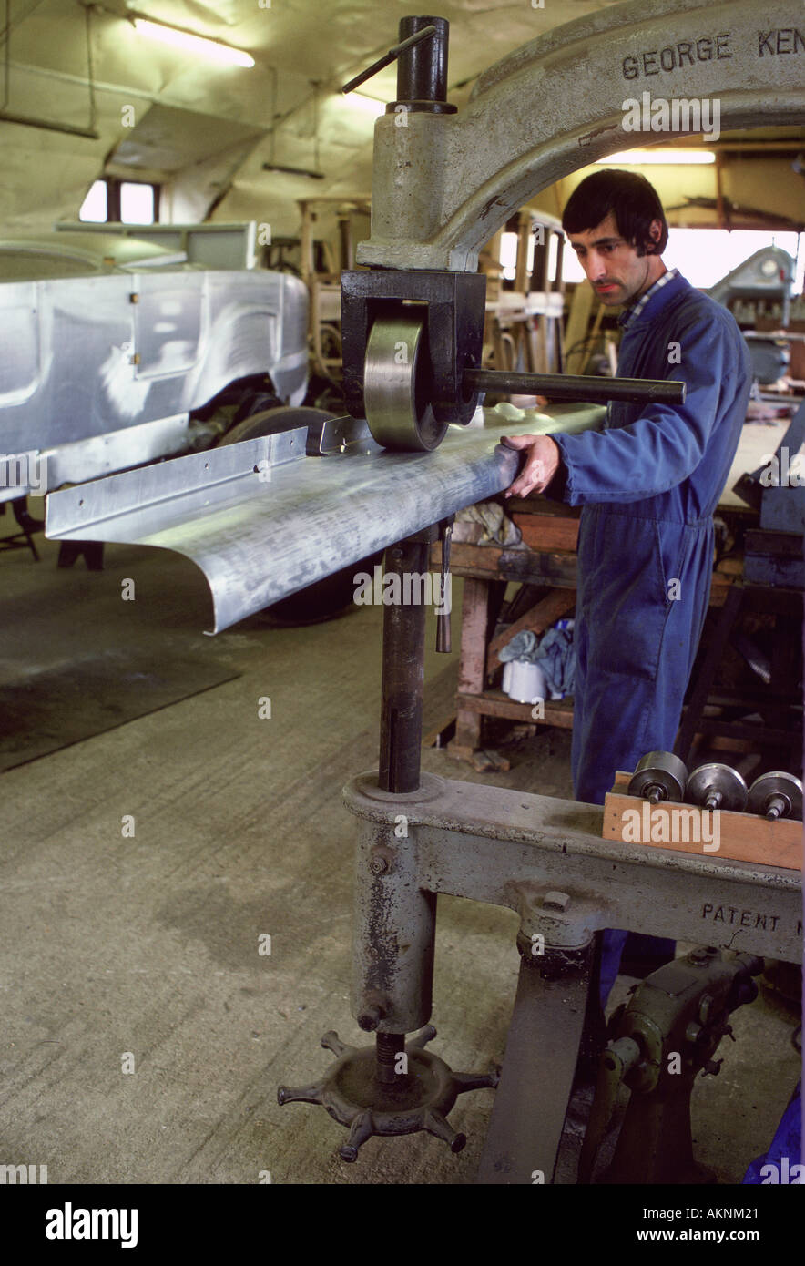 Man rolling an aluminium panel during the restoration of a rare vintage ...