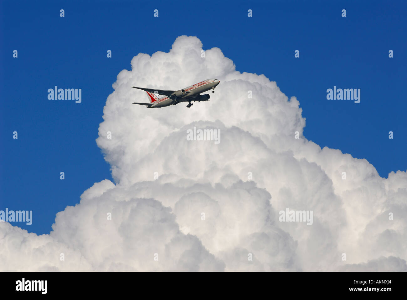 Lone Air India jet airplane amongst cumulonimbus clouds and blue sky ...