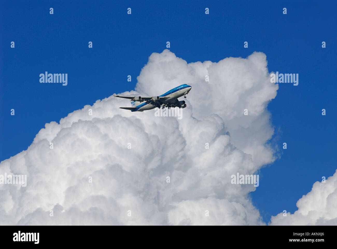 Lone KLM jumbo jet airplane amongst white cumulonimbus clouds on blue ...
