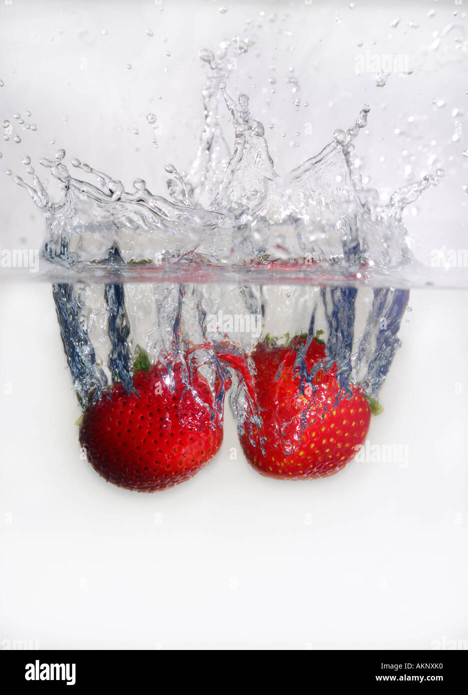 Two splashing strawberries dropped into water high speed frozen splash ...