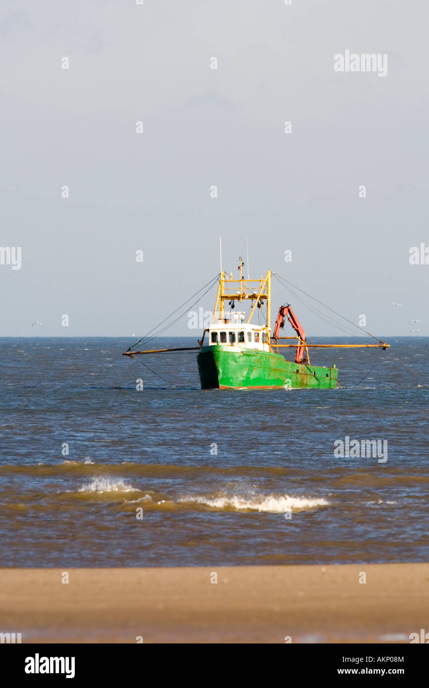 Trawler working near beach Stock Photo - Alamy
