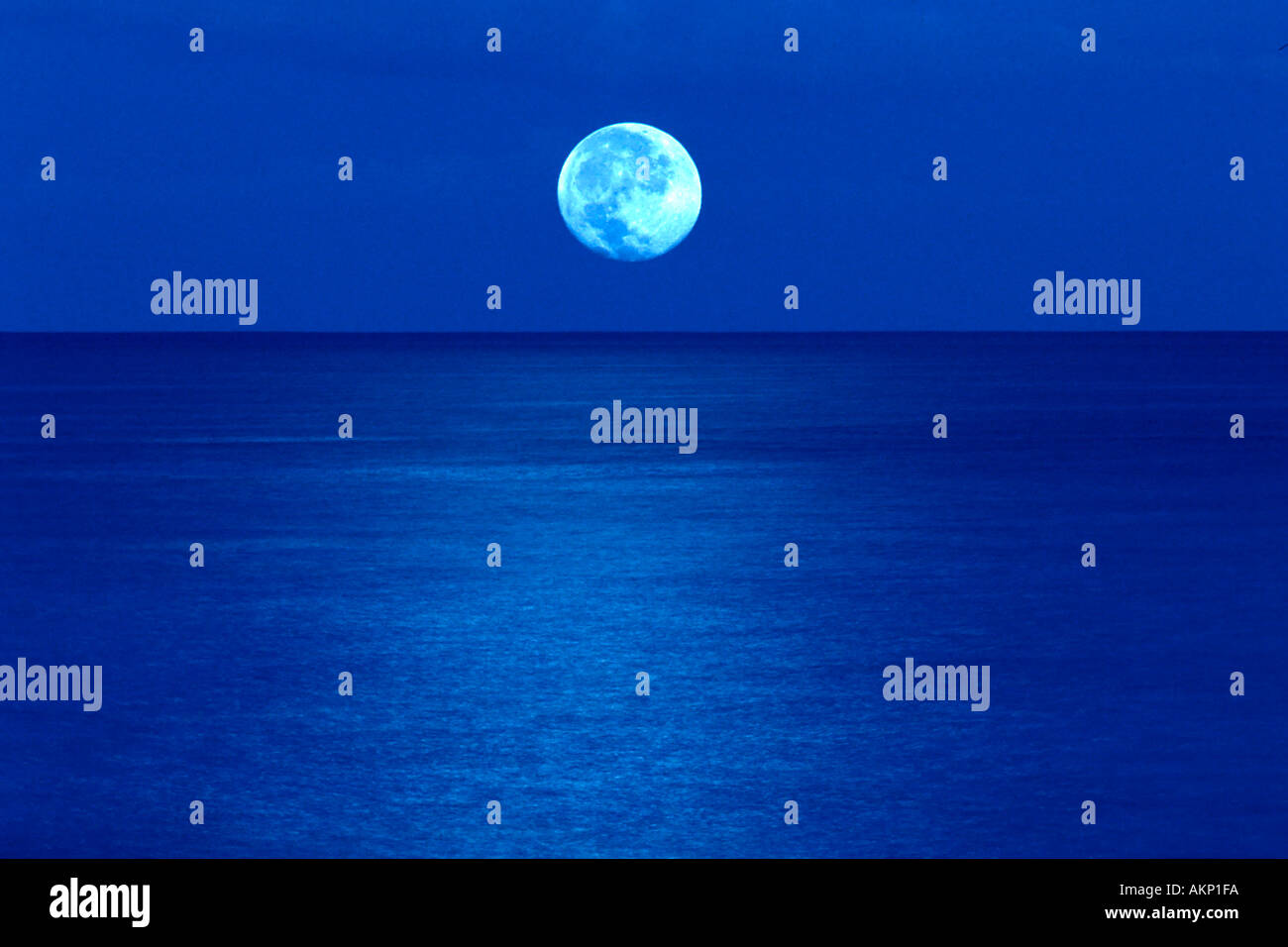 Full moon sets over the ocean Stock Photo - Alamy