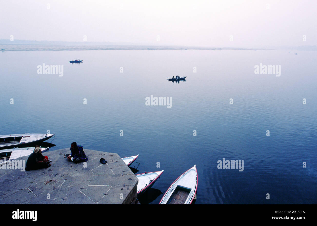 Water edge of river Ganges with boats and people sitting on the steps ...