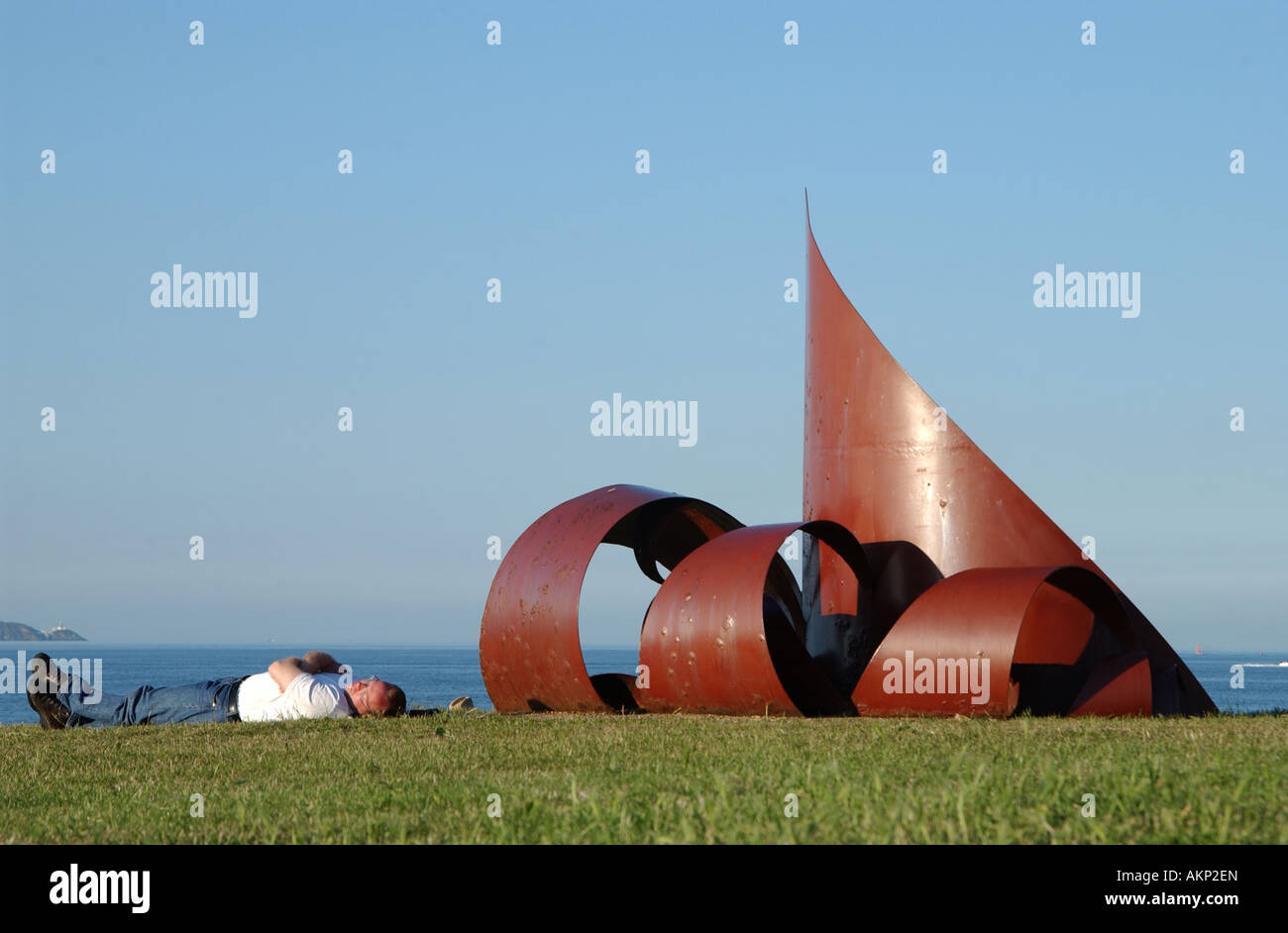 A man takes a nap beside some public art on a hot summers day in Dun ...