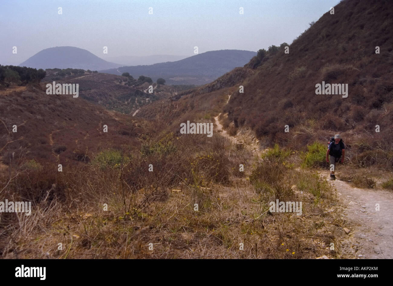 A hiker walks on the Israel National Trail near Mount Tabor (far left ...
