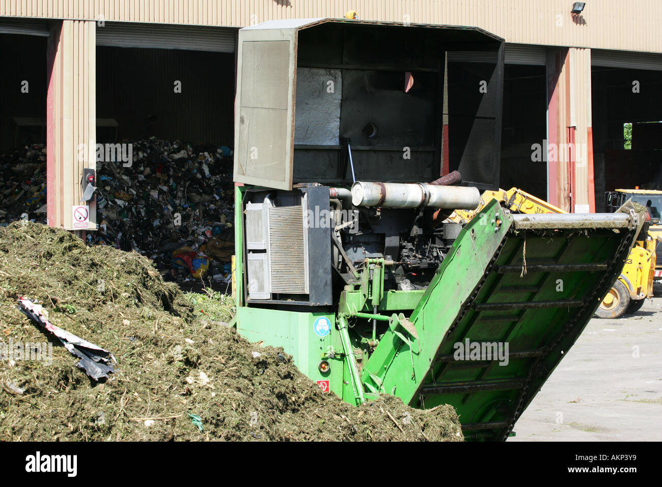 A garden rubbish shredder machine sits beside a pile of recycled garden ...