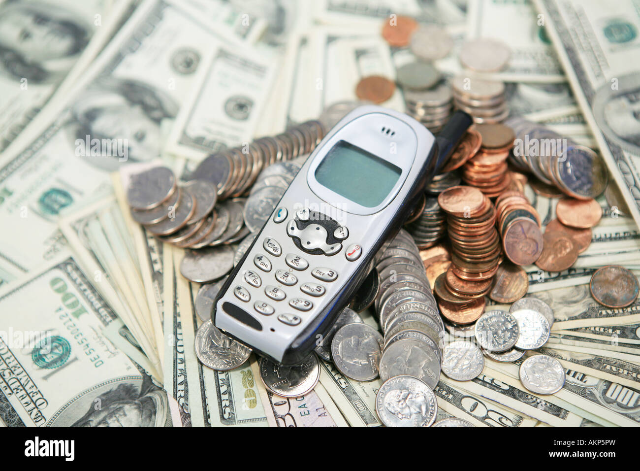 Cell phone on top of pile of American money coins and bills Stock Photo ...