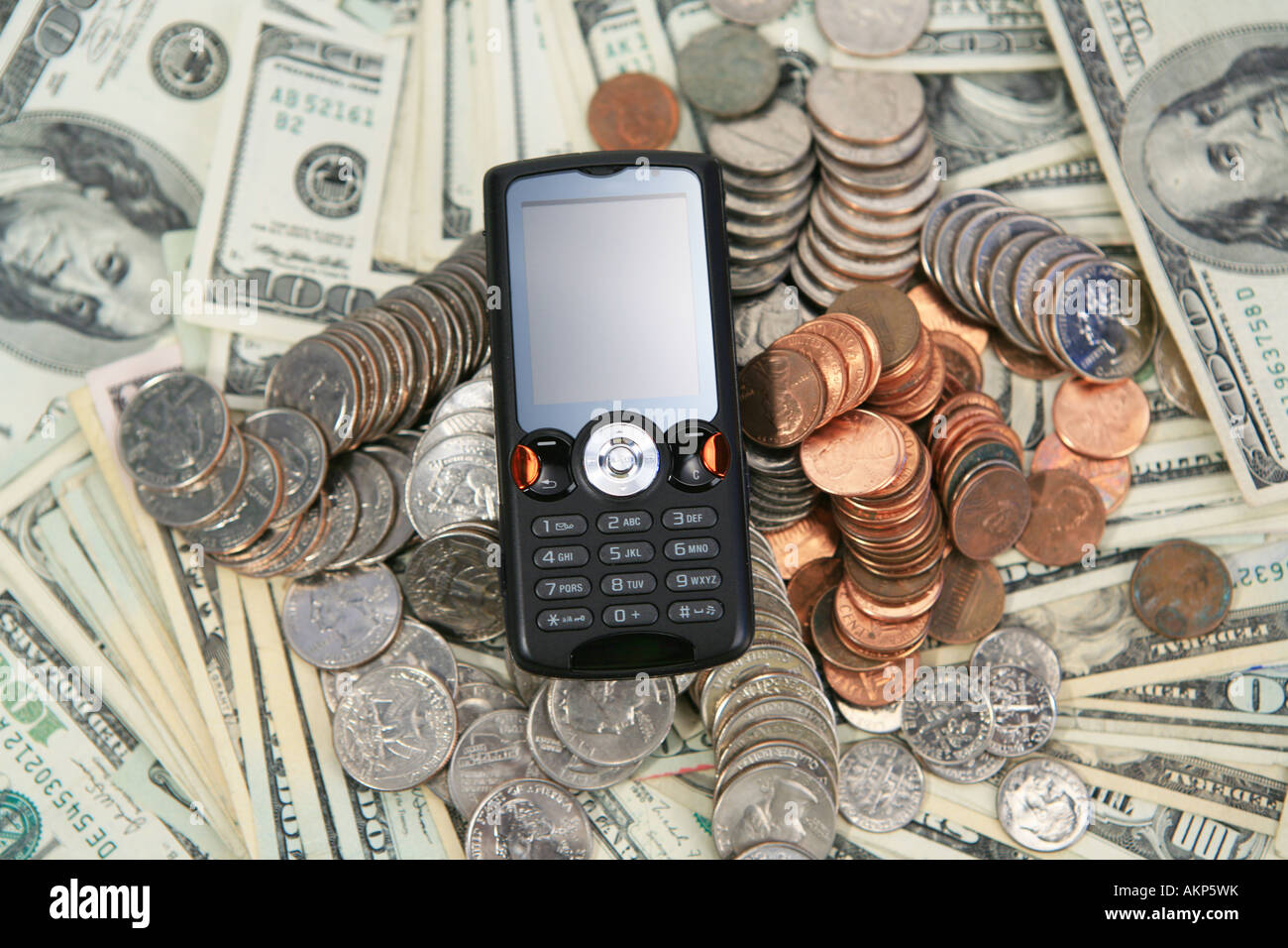 Cell phone on top of pile of American money coins and bills Stock Photo ...