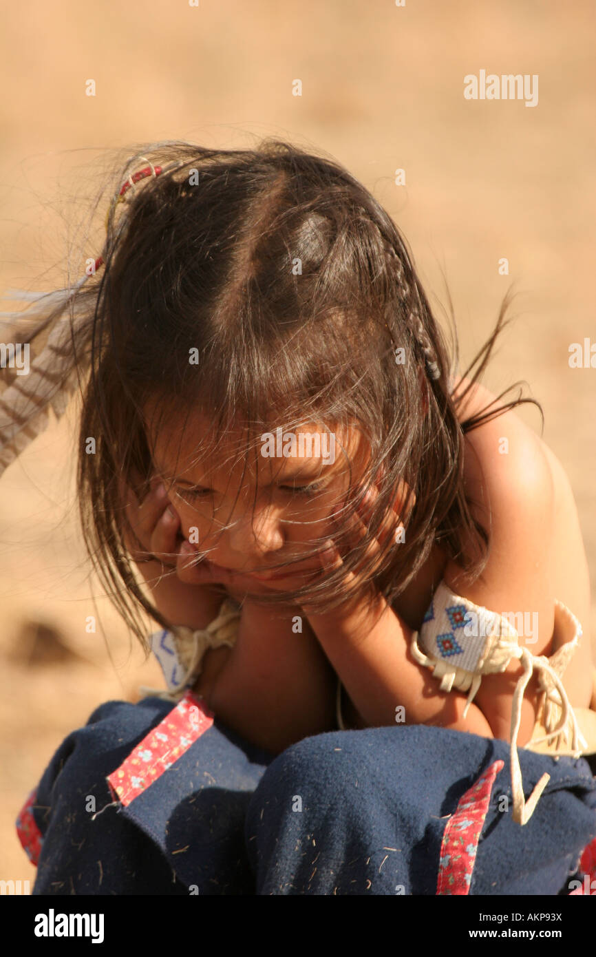Young Native American boy sitting on a log looking distraught or upset ...