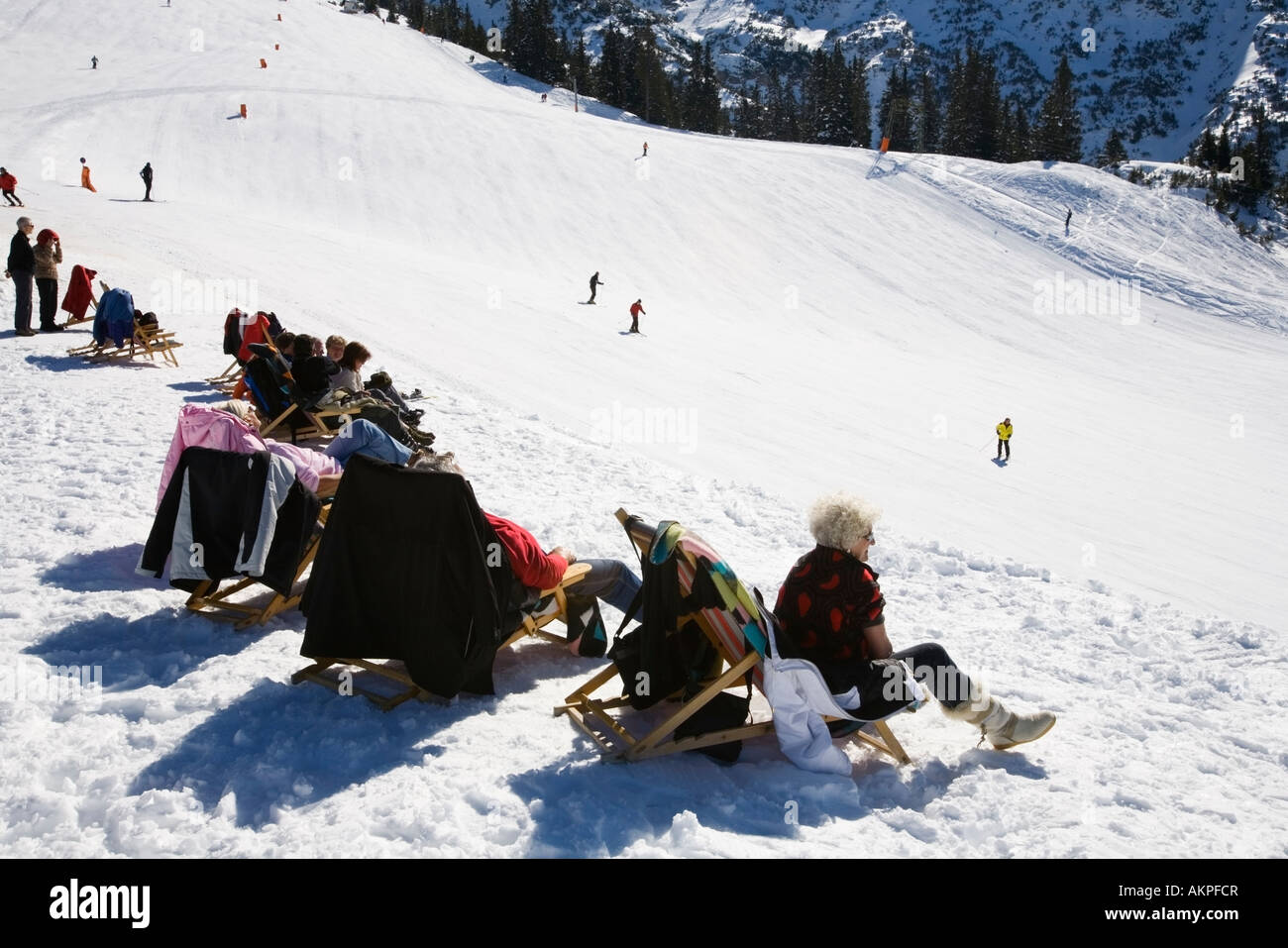 people seated in deck chairs watching the skiing on the slopes Stock ...