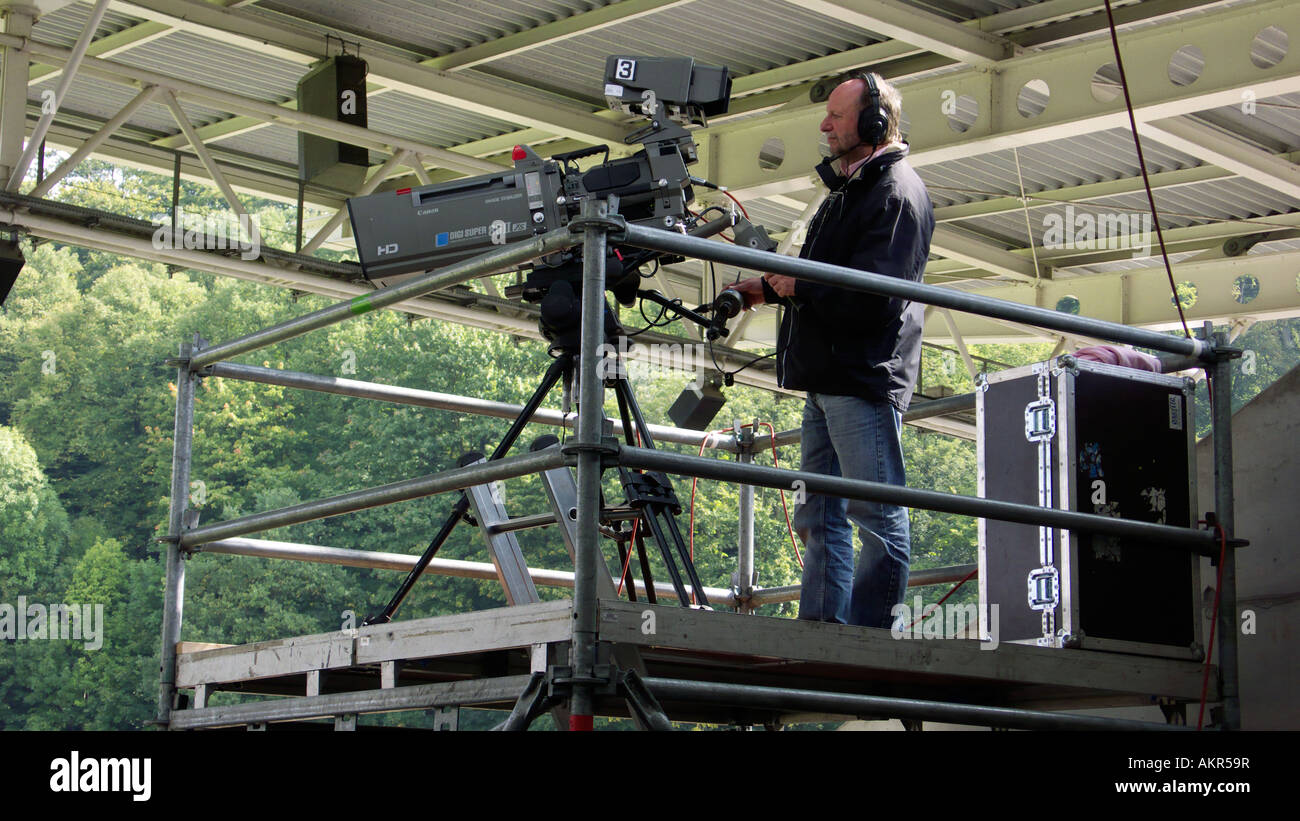 cameraman with a TV camera on a steel tube stage, platform, football ...