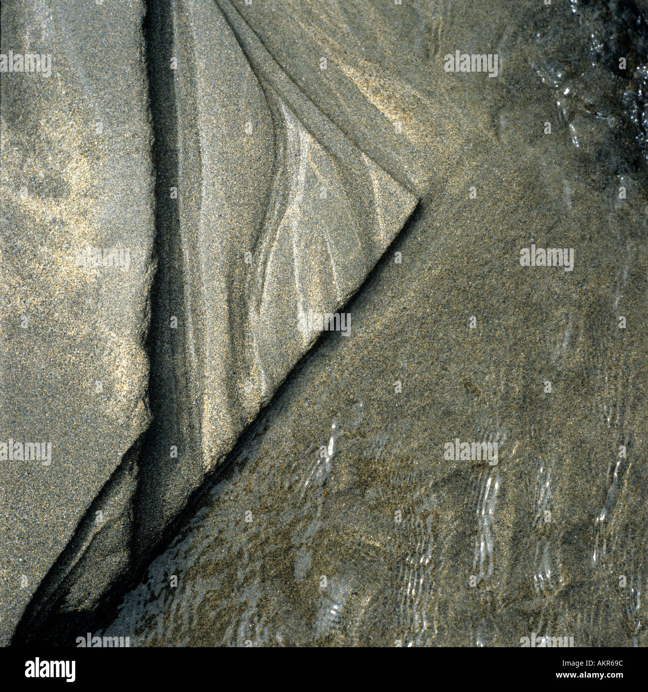 Fine pale beach sand eroded by running rippling stream foreshore Reiff ...