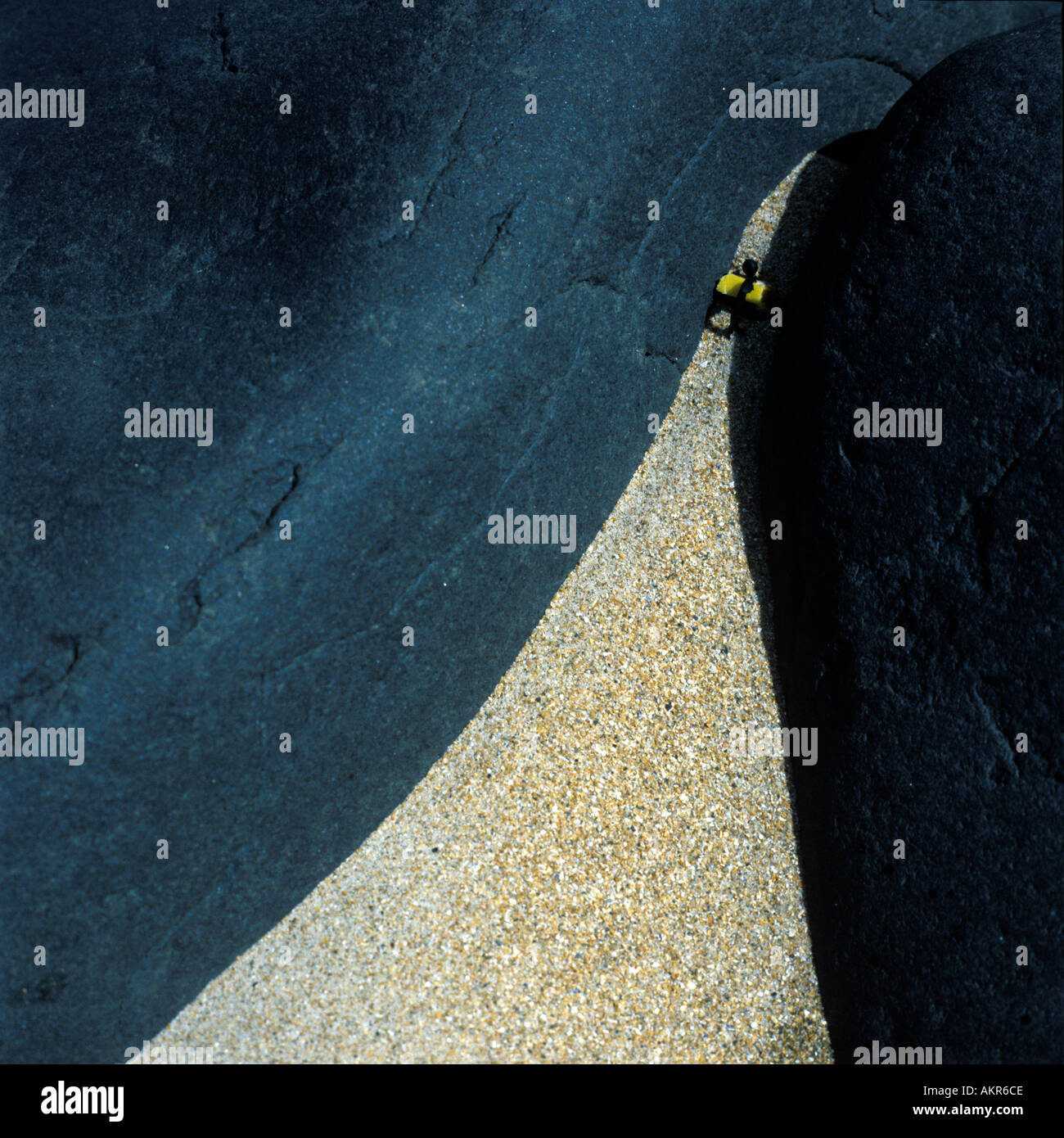Abstract of dark blue rock flanking clean bright pale yellow sand with ...