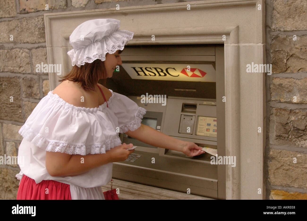 Young woman in fancy dress costume drawing money from HSBC Bank cash ...