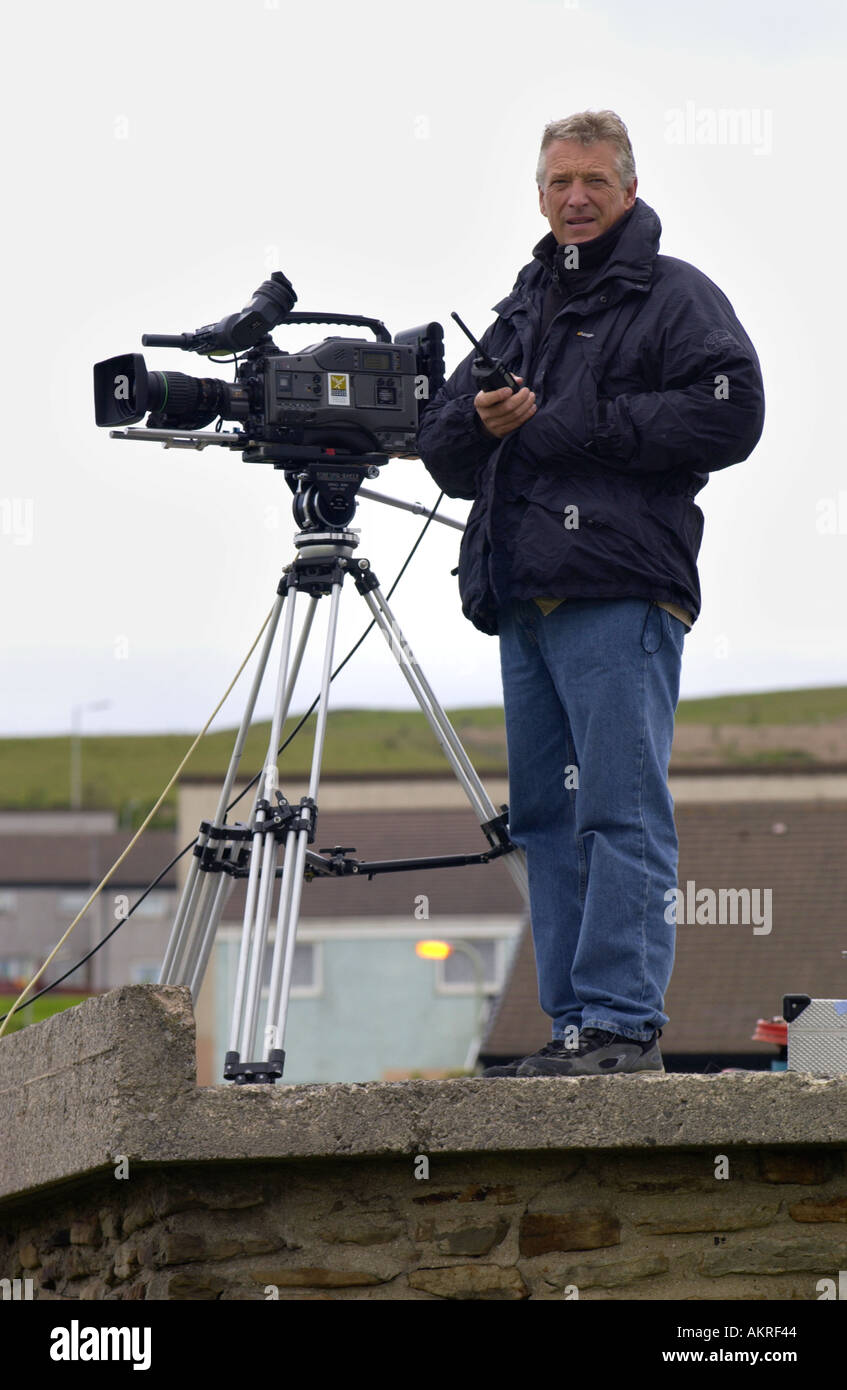 Film cameraman working on location standing on a wall in a housing ...