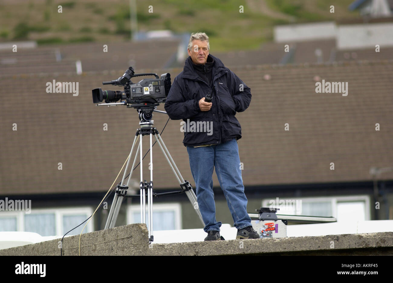 Film cameraman working on location standing on a wall in a housing ...