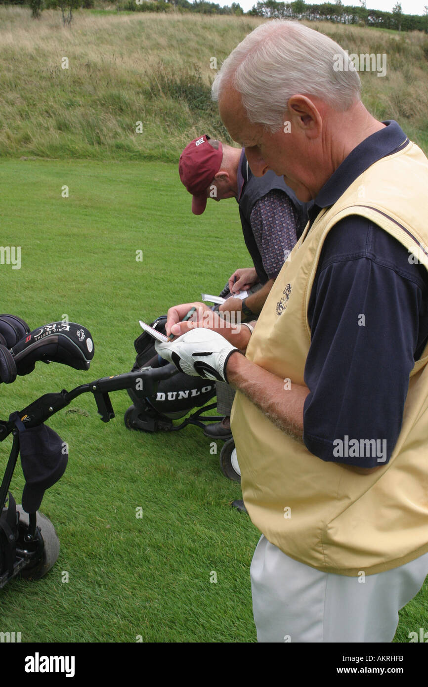 group of golfers writing down their scores on their scorecards after a ...