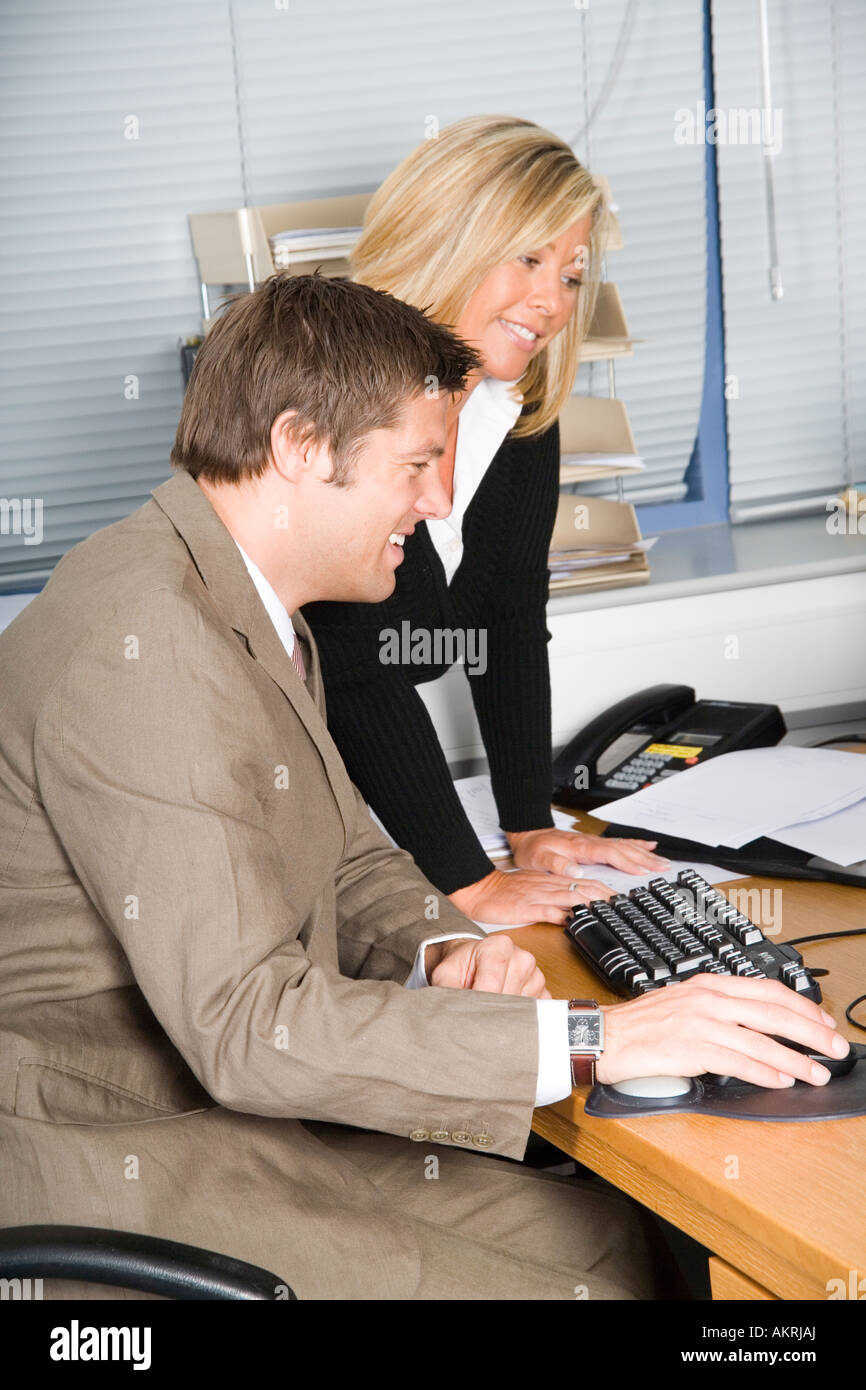 Two young business people working on a computer in a modern office ...