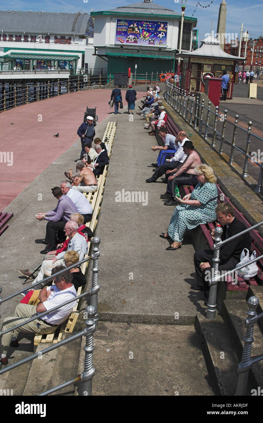 people sitting on the seats on the promenade overlooking the sea at ...