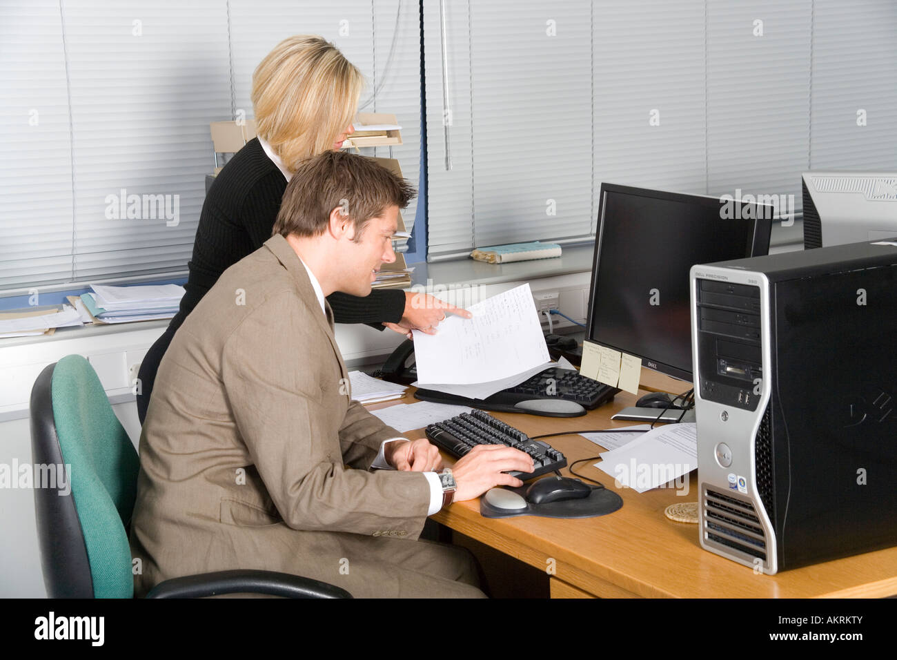 Two young business people working on a computer in a modern office ...