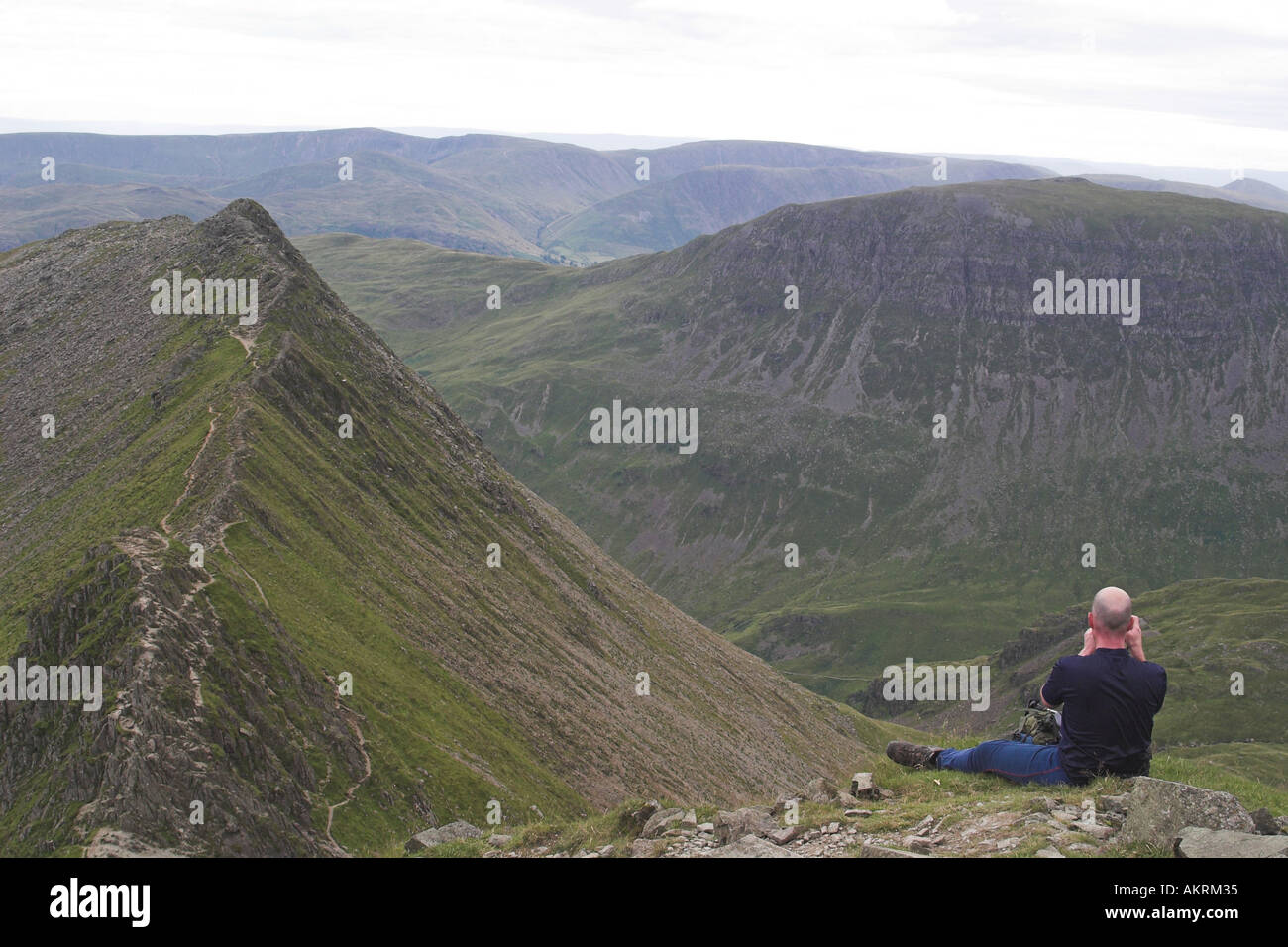 man sitting admiring the view from hellvelyn down to striding edge in ...