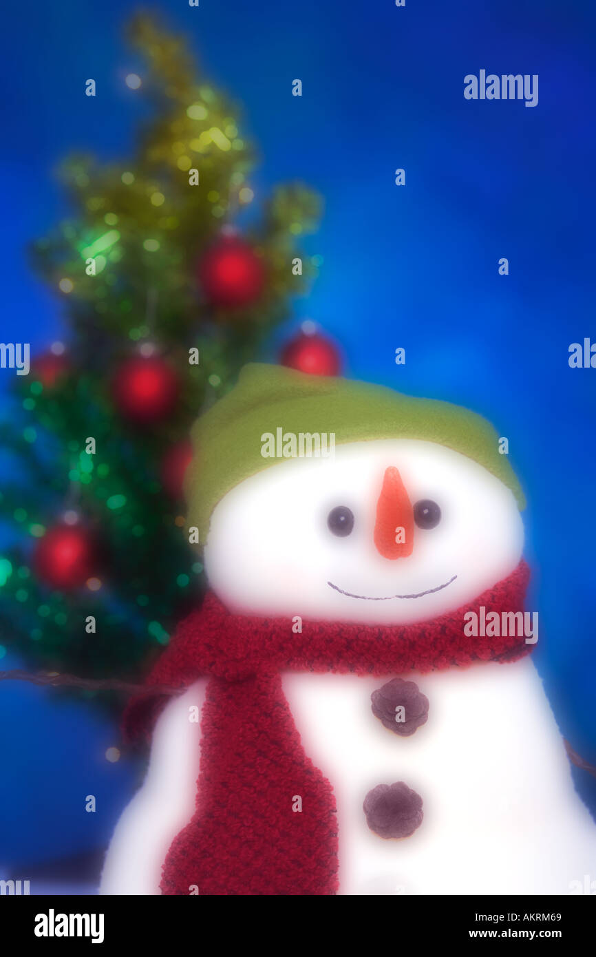 Artificial snowman with a big smile in front of a green artificial ...