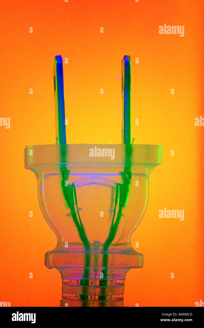 Clear Electric Plug lit with blue and green against a red and yellow ...