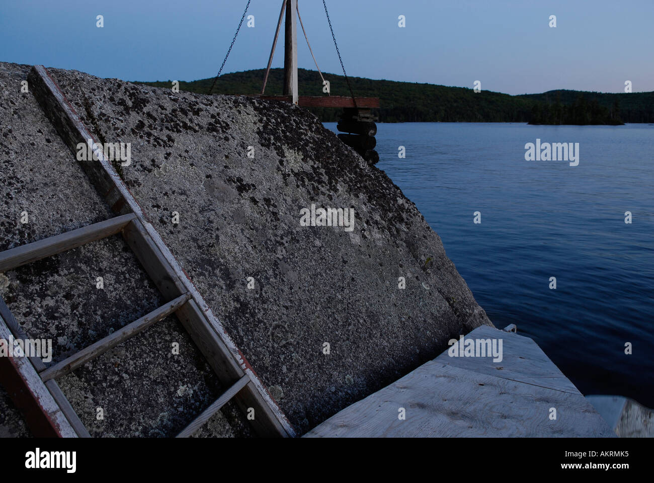 Stock image of huge stone and dock at night under a full moon on a lake ...