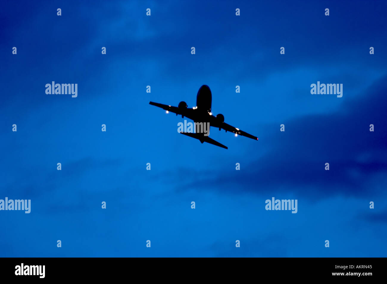 Single airplane in the sky at twilight with clouds Stock Photo - Alamy