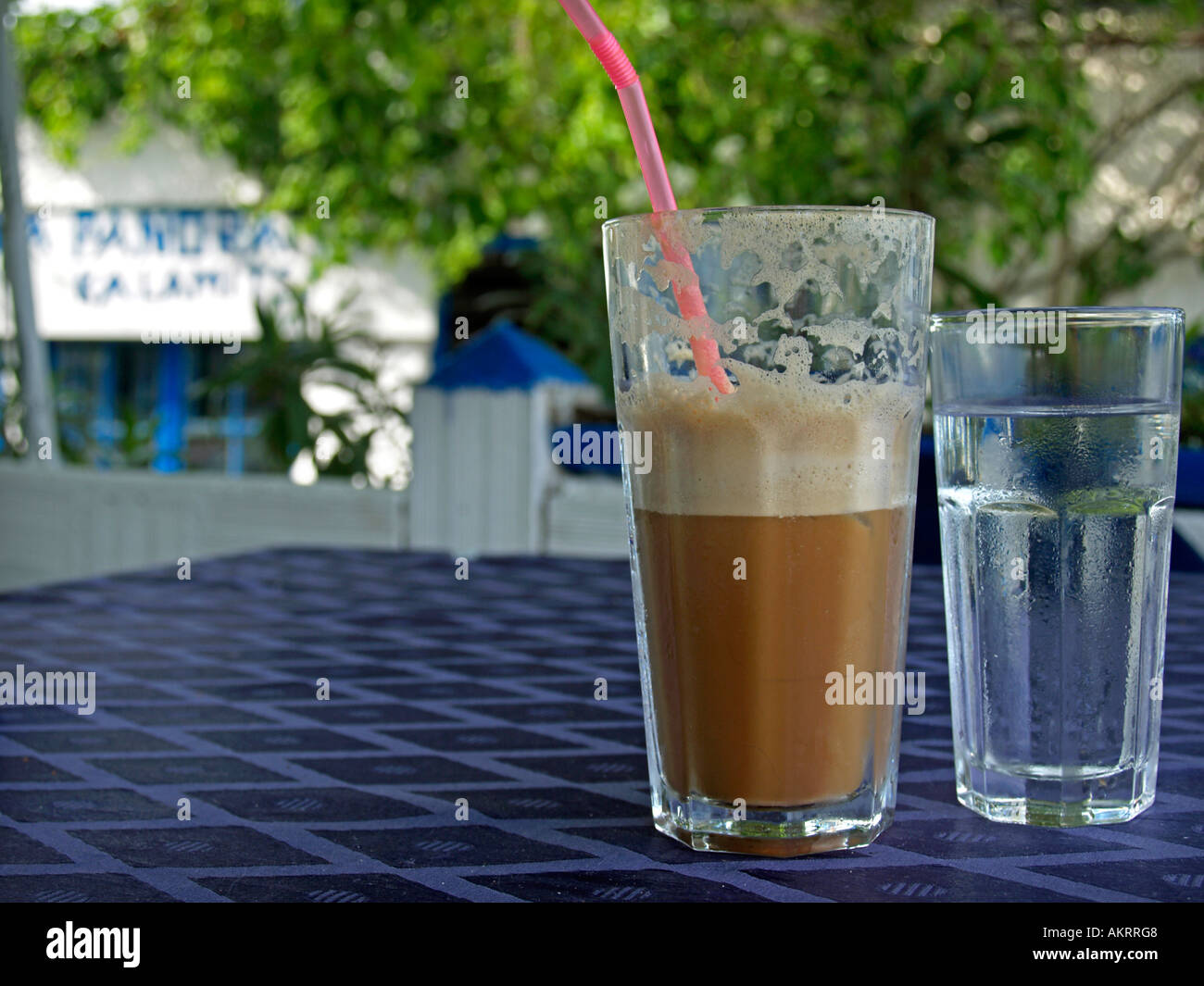 frappe frappé cold coffee with foam and glass filled with cold water on ...