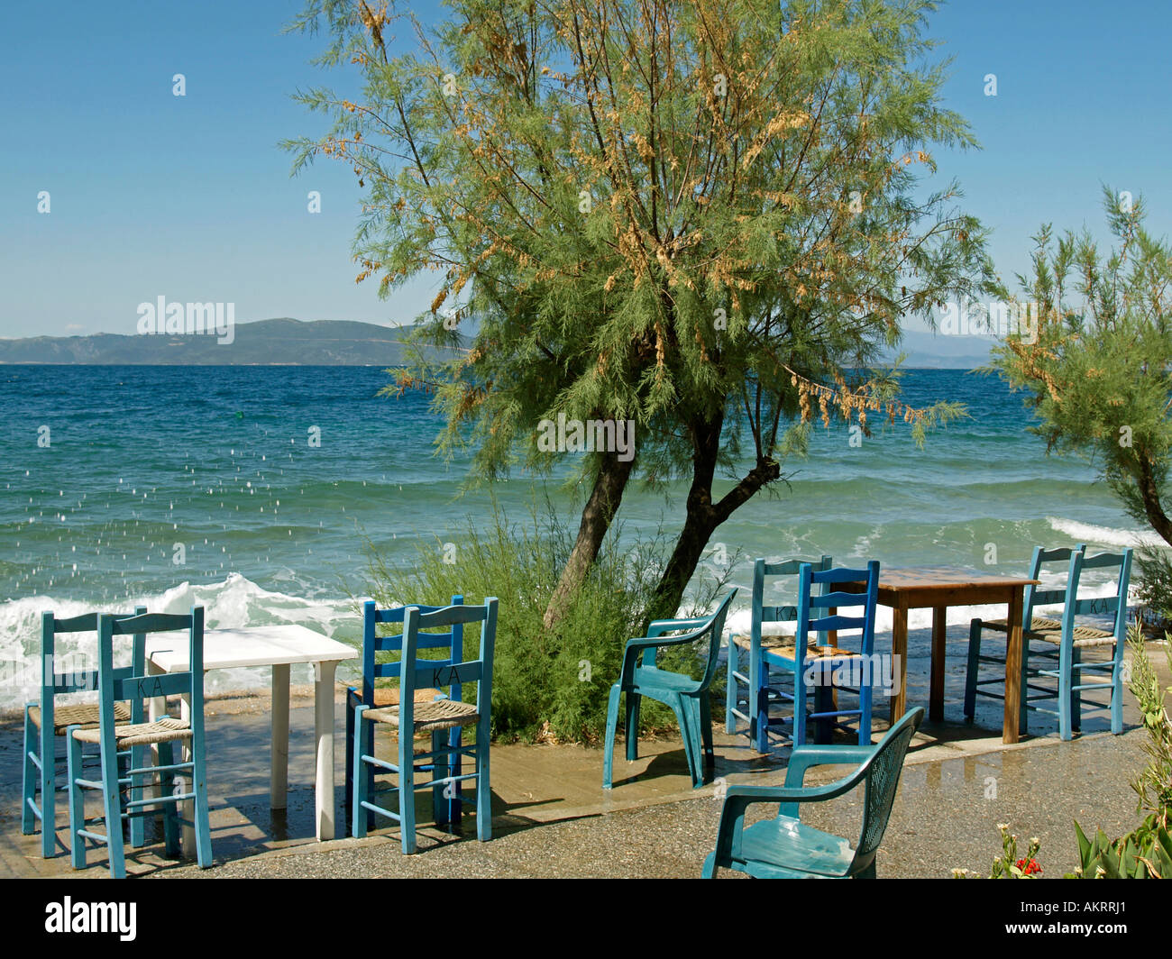 tables and chairs of a greek kafenion bar restaurant close by the sea ...