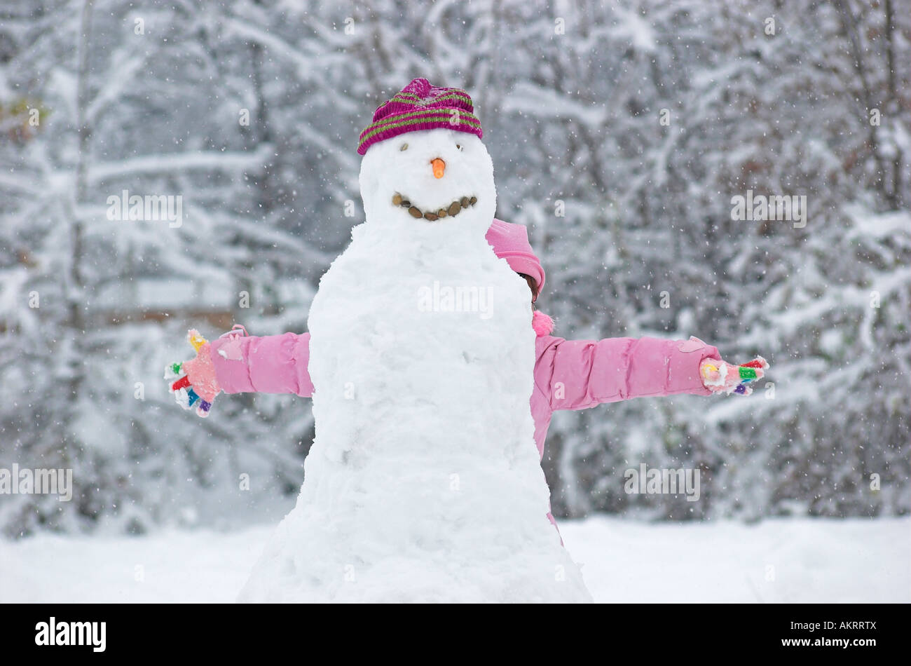 Girl 2 4 standing behind snowman with open arms Stock Photo - Alamy
