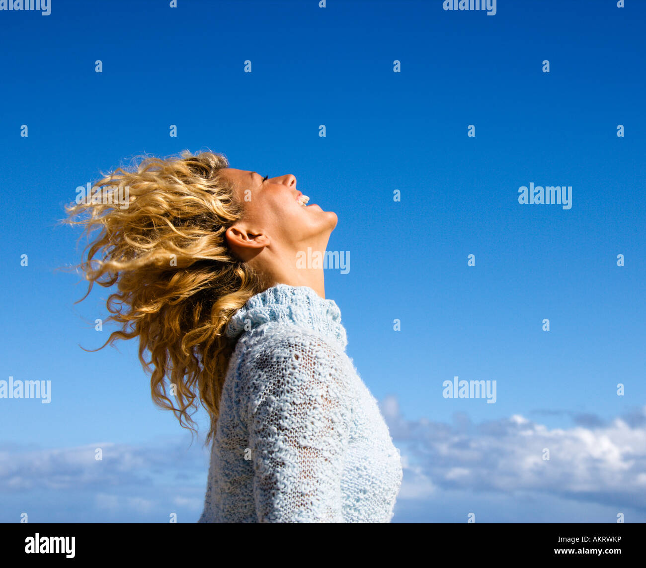 Side view of pretty woman holding head back smiling with hair flowing ...