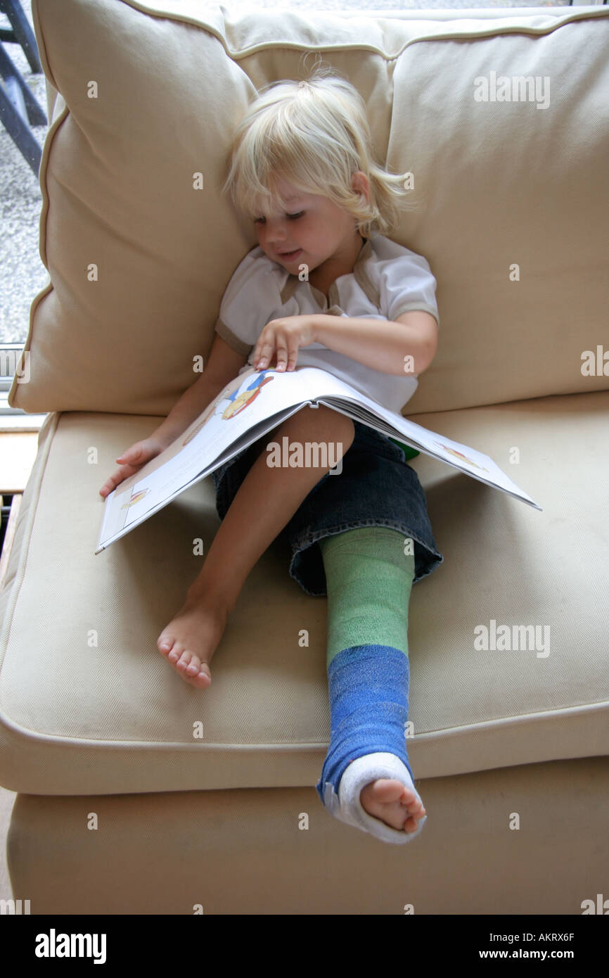 Little boy with a broken leg reading a book Stock Photo - Alamy