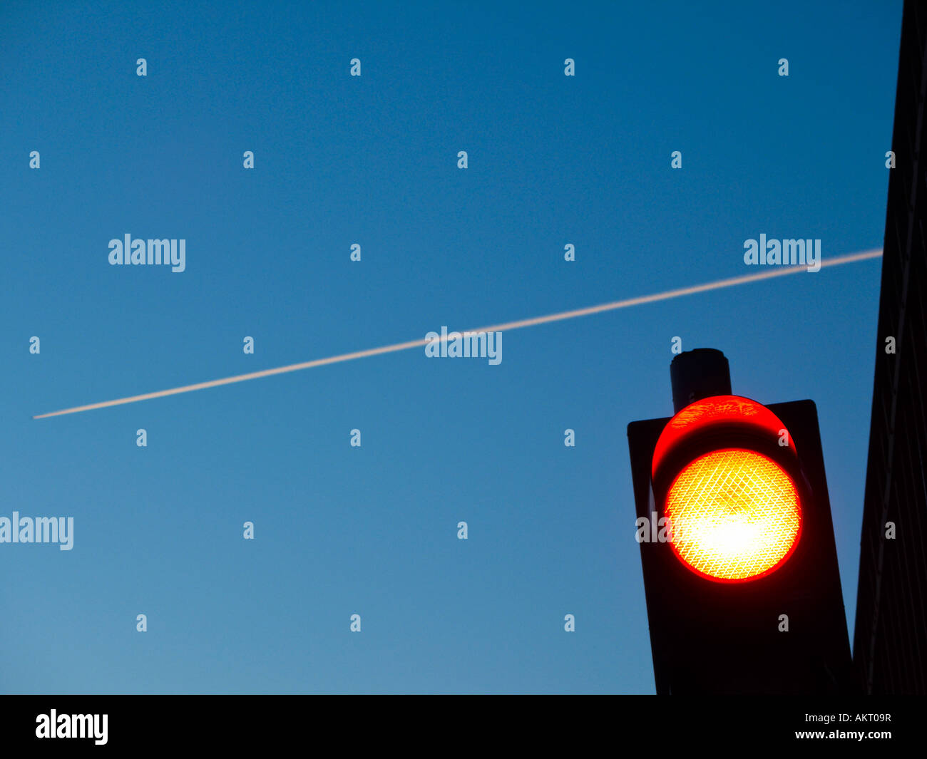 Red traffic light and jet trail on blue sky Stock Photo - Alamy
