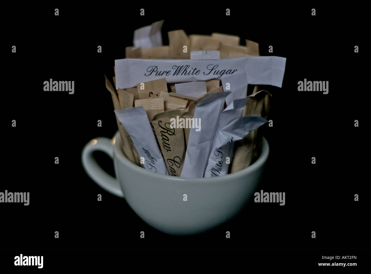 Sugar bowl with brown and white sugar sachets on a black background ...