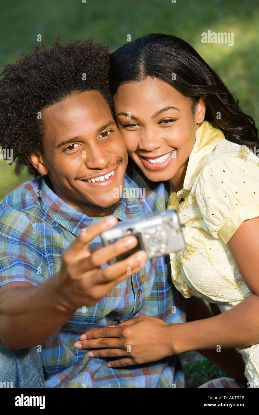 Happy smiling couple taking pictures together in park with digital ...