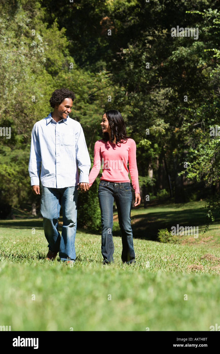 Smiling couple holding hands walking and talking in park Stock Photo ...