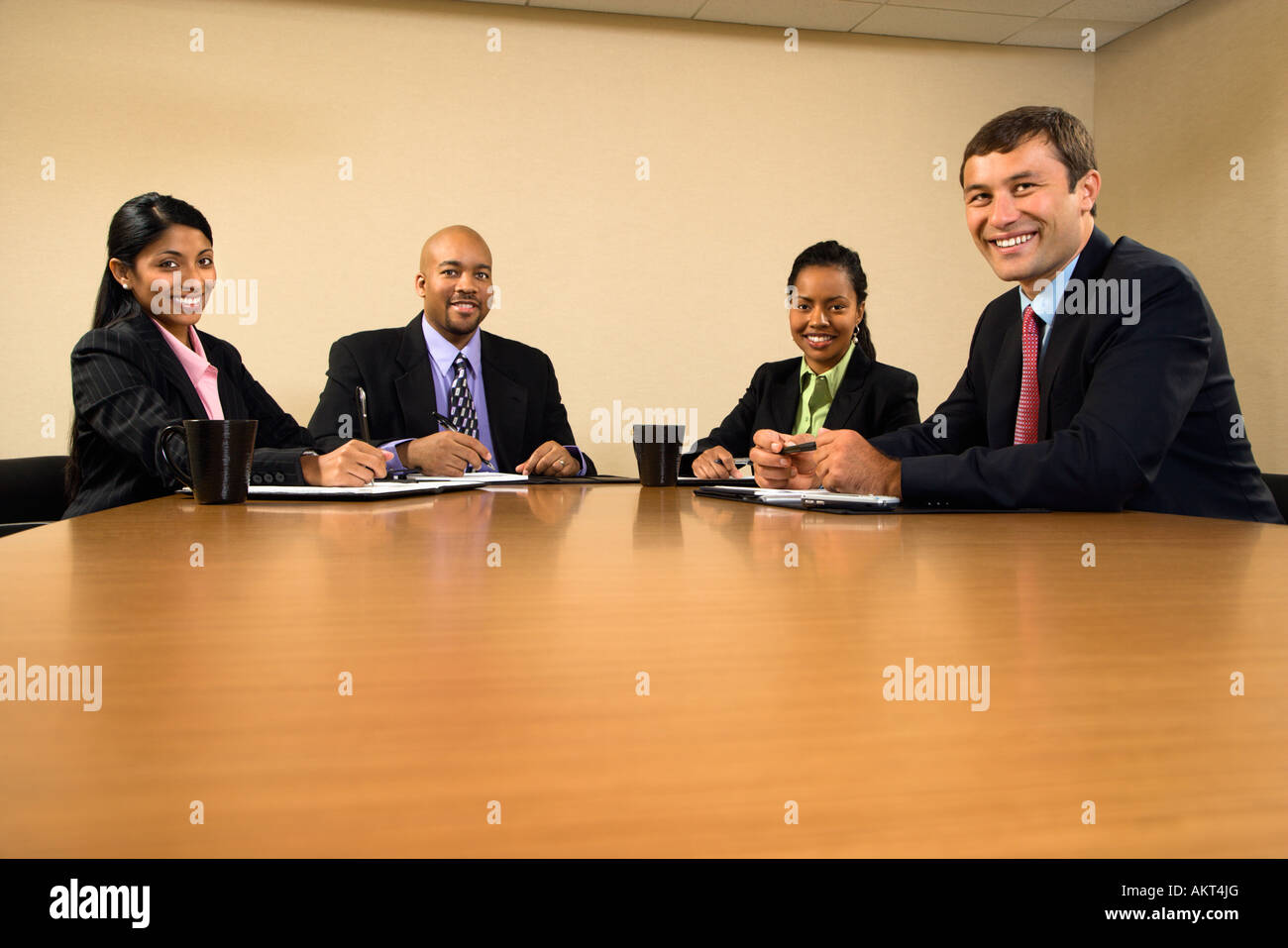 Businesspeople sitting at conference table smiling Stock Photo - Alamy