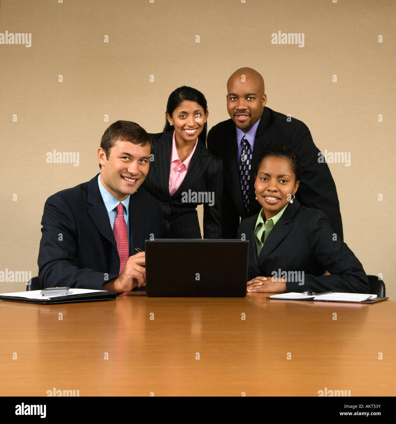 Businesspeople gathered around laptop computer smiling Stock Photo - Alamy
