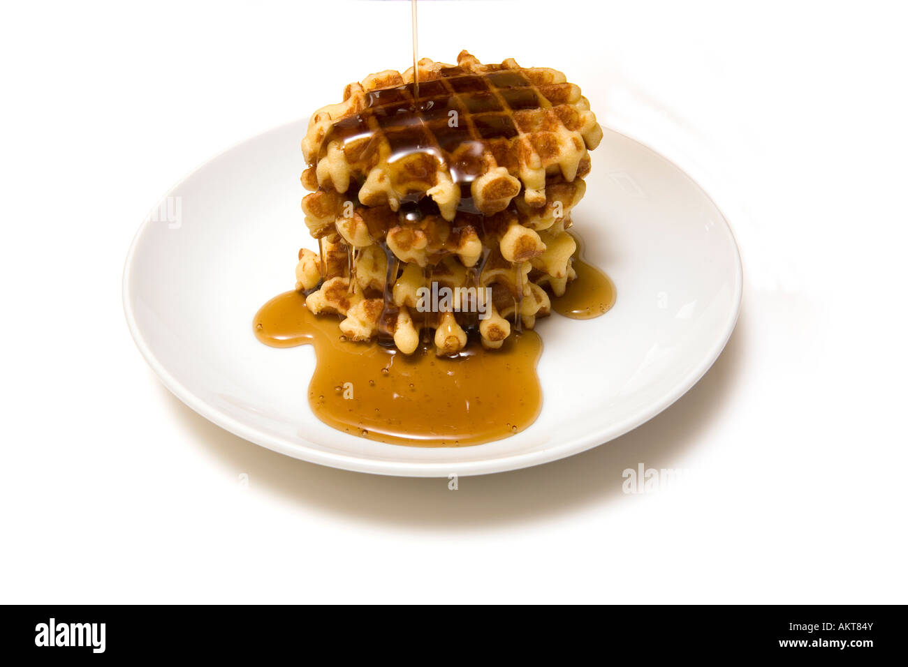 Belgian butter waffles and maple syrup on a white plate and background ...